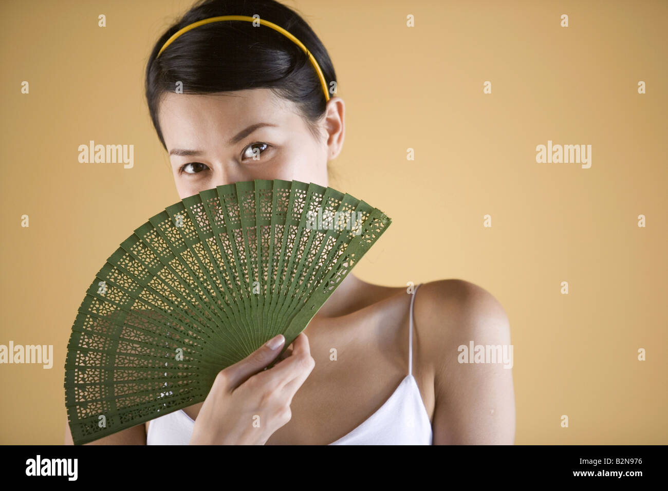 Portrait of a young woman hiding her face with a folding fan Stock ...