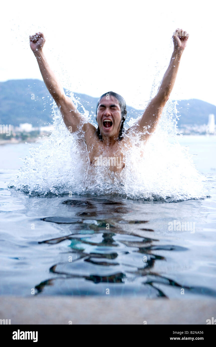 Young man shouting with arms raised in a swimming pool, Phuket ...