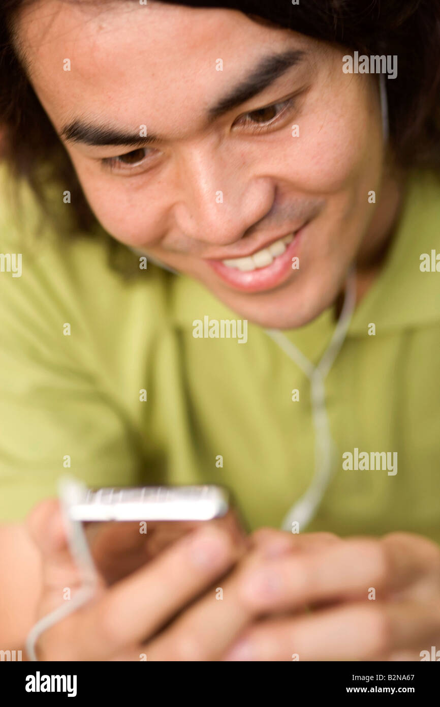 Close-up of a young man listening to an MP3 player and smiling Stock ...