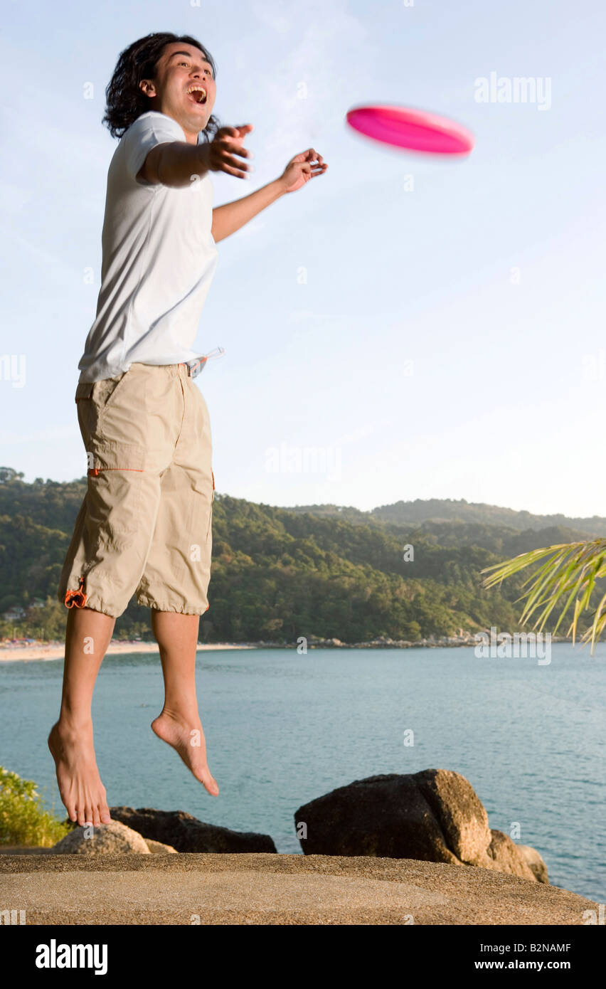 Side profile of a young man throwing a plastic disc, Phuket, Thailand ...