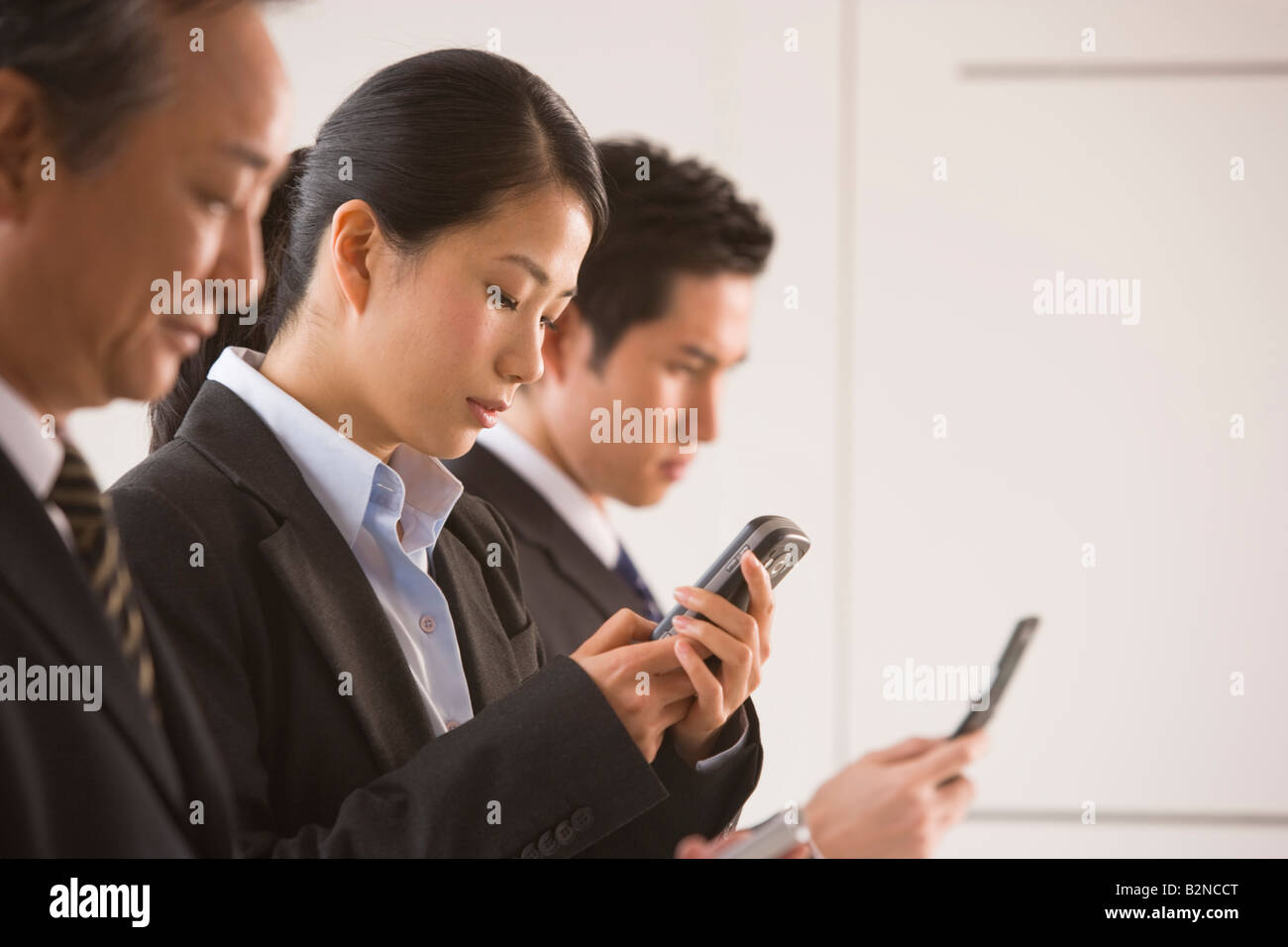 Three business executives using their mobile phones Stock Photo - Alamy