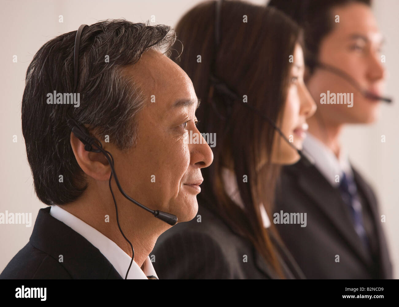 Three business executives wearing headsets Stock Photo - Alamy