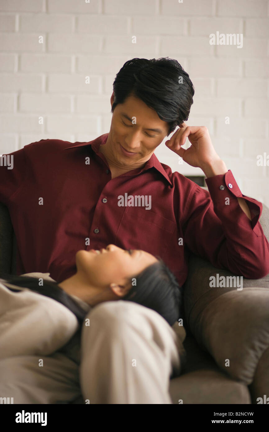 Young woman resting on the lap of a young man on a couch Stock Photo ...