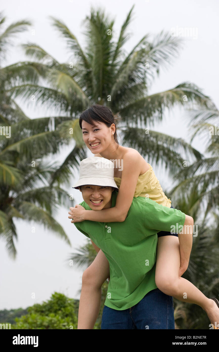 Mid adult man giving piggyback to a mid adult woman and smiling Stock ...