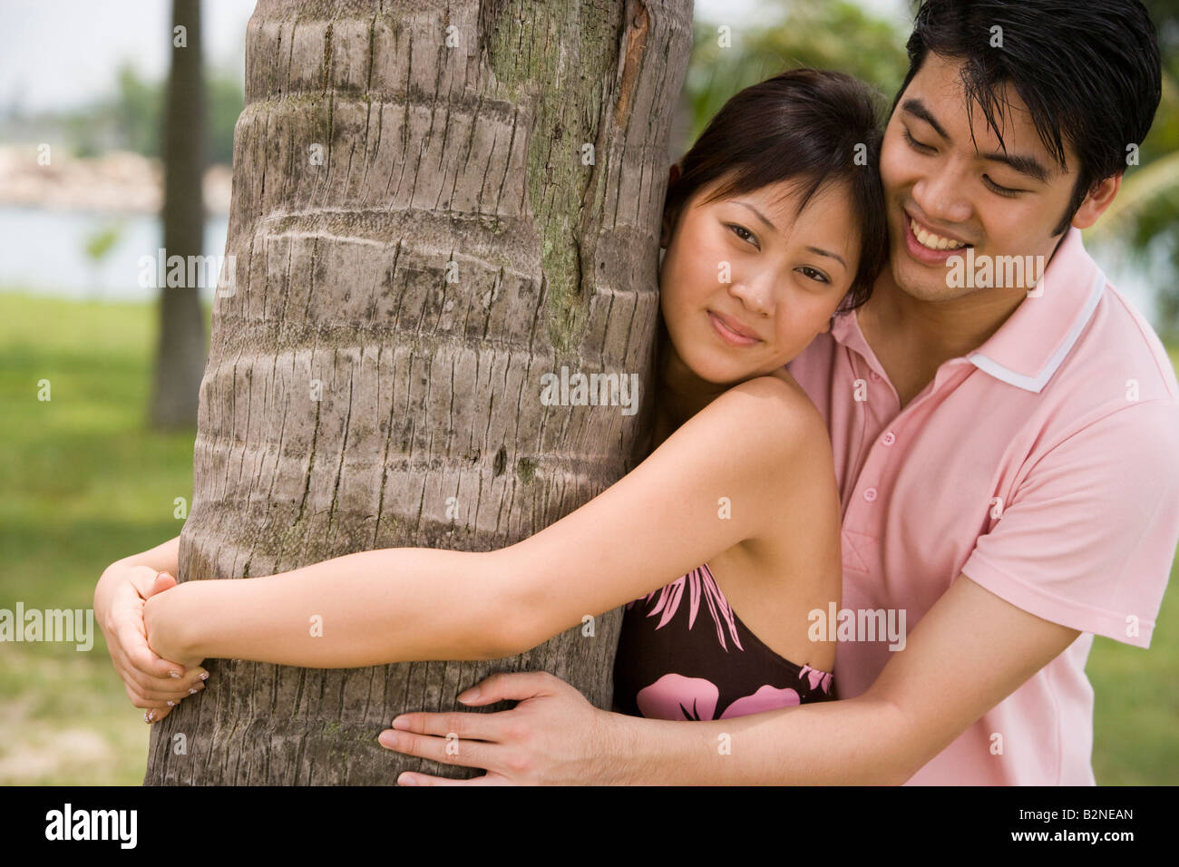 Close-up of a young couple hugging a tree trunk Stock Photo - Alamy