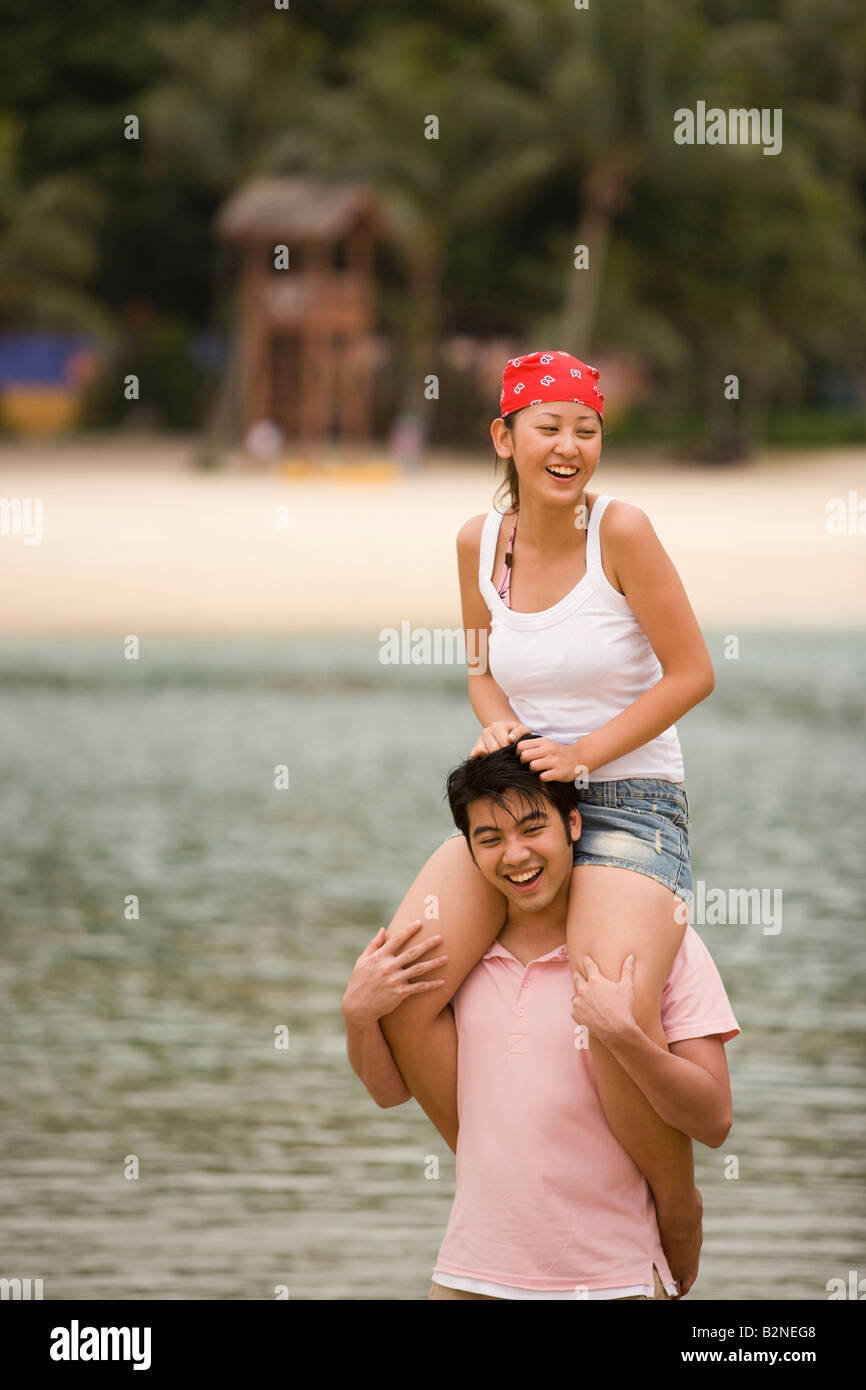 Young woman sitting on a young man's shoulders on the beach Stock Photo ...