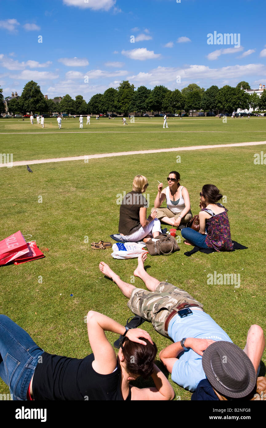 People relax and watch a game of cricket on warm summer afternoon The ...