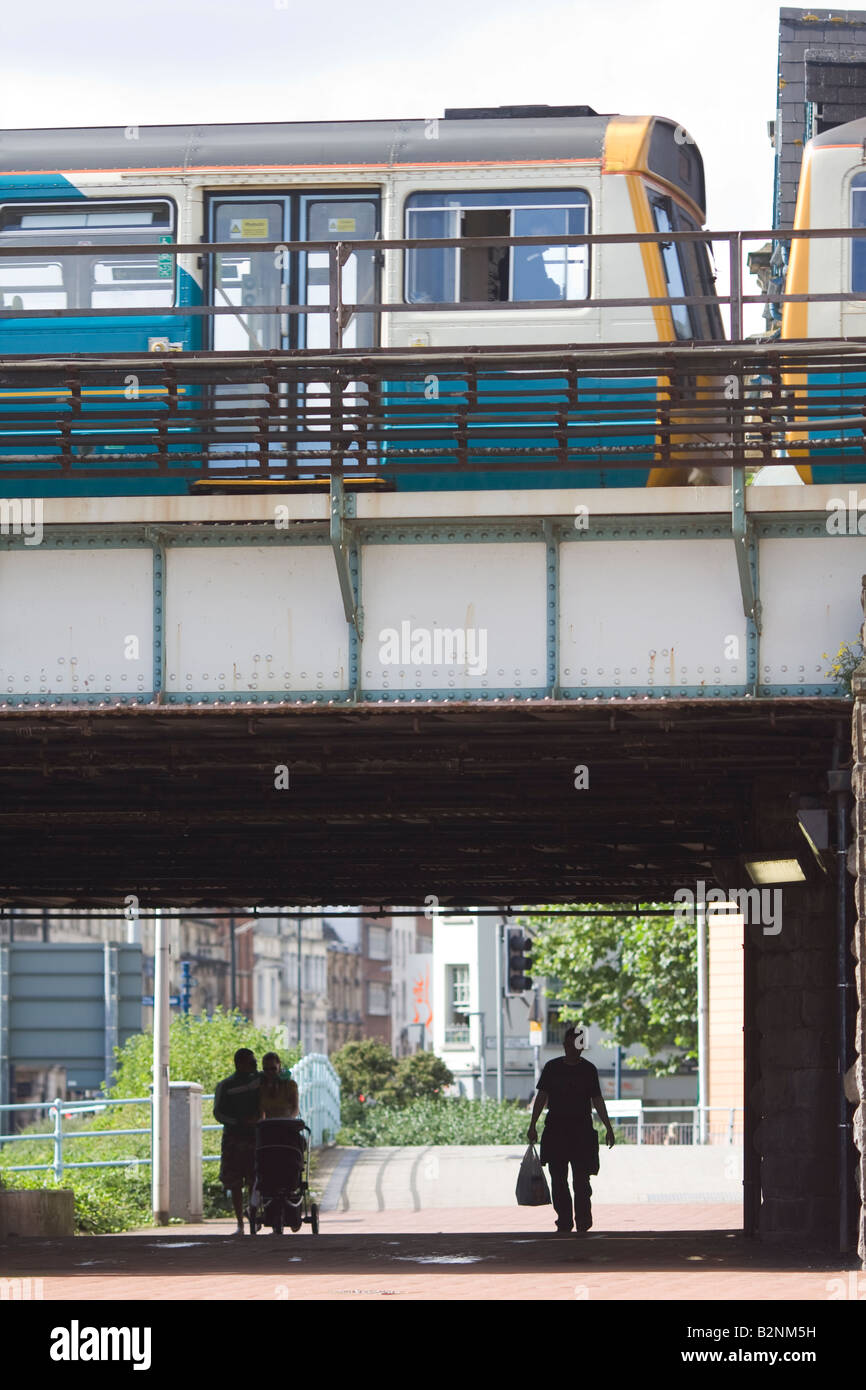 Walkers in subway underneath the main rail line with a commuter train ...