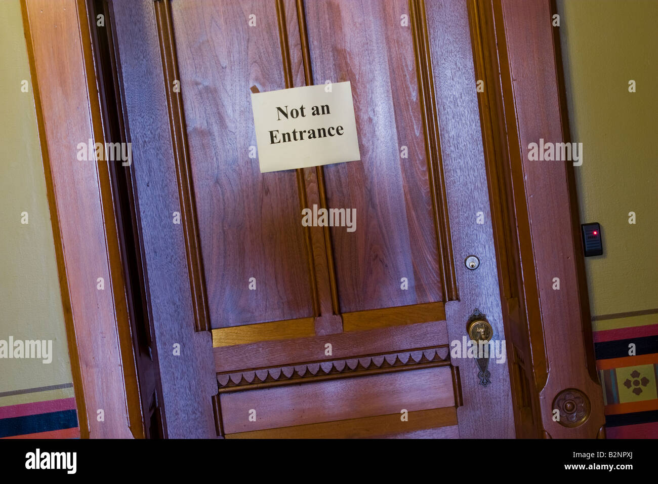 Wooden office door with a sign reading Not an Entrance taped to it ...