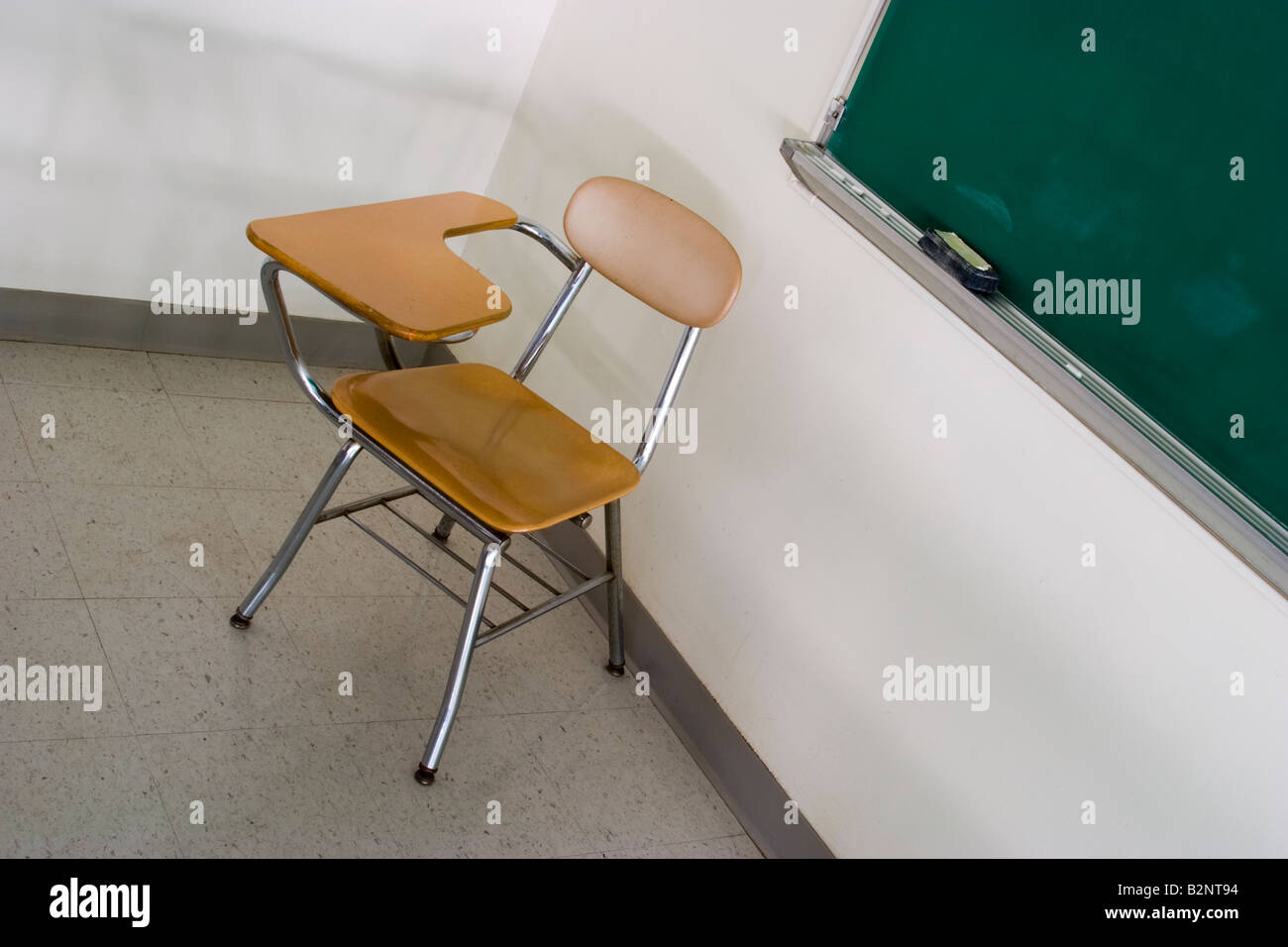 Chair and desk combination next to a green chalkboard in a college ...