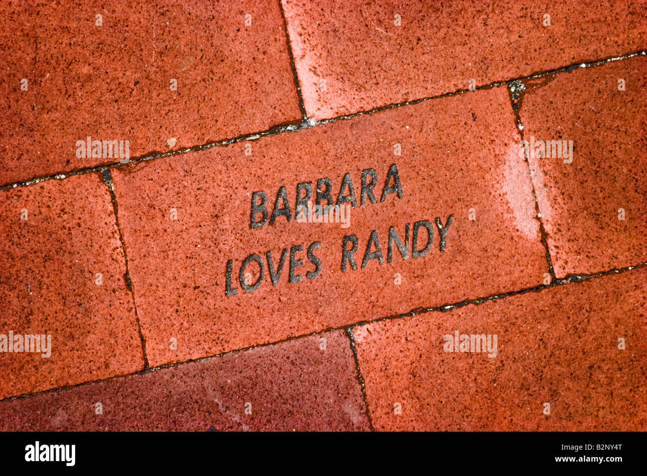 Brick on a city sidewalk reading Barbara Loves Randy Stock Photo - Alamy