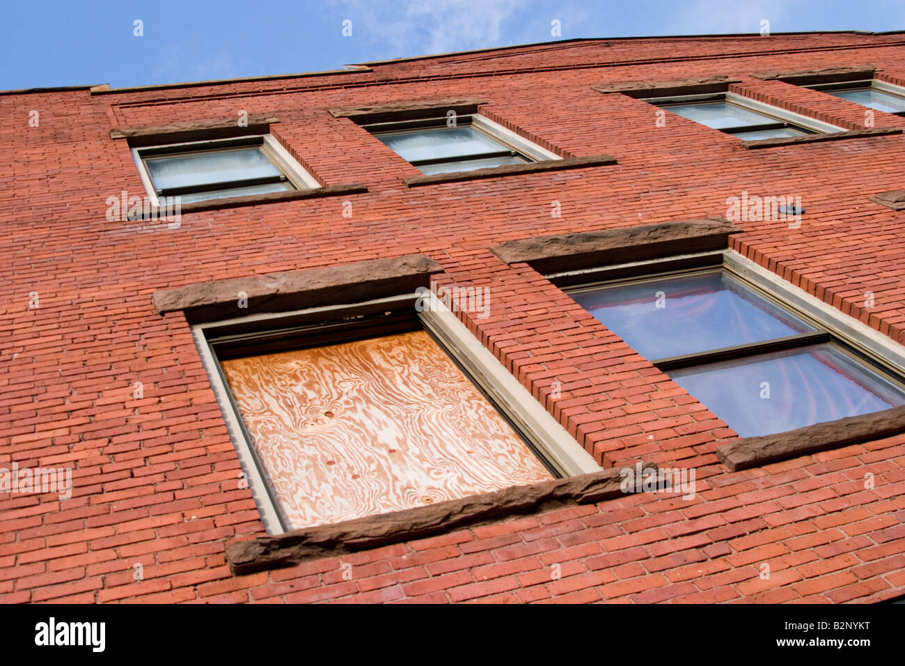 Exterior wall of a brick office building with one window boarded up ...