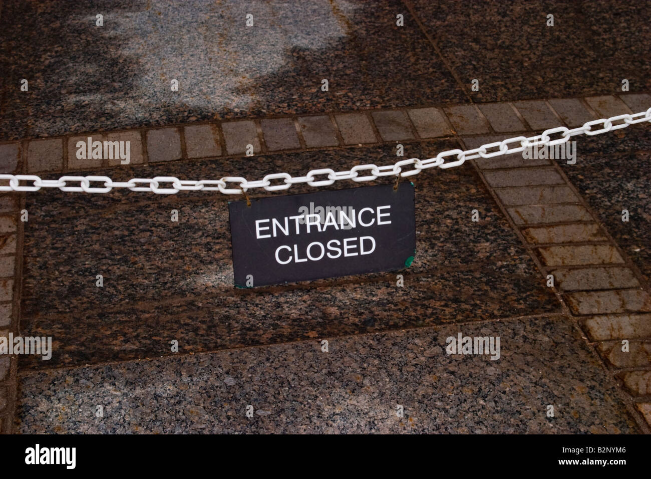 Entrance to a building blocked with a chain and a sign reading ENTRANCE ...