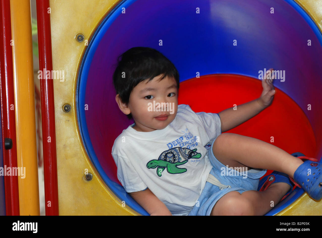 Toddler sitting on tube slide Stock Photo - Alamy
