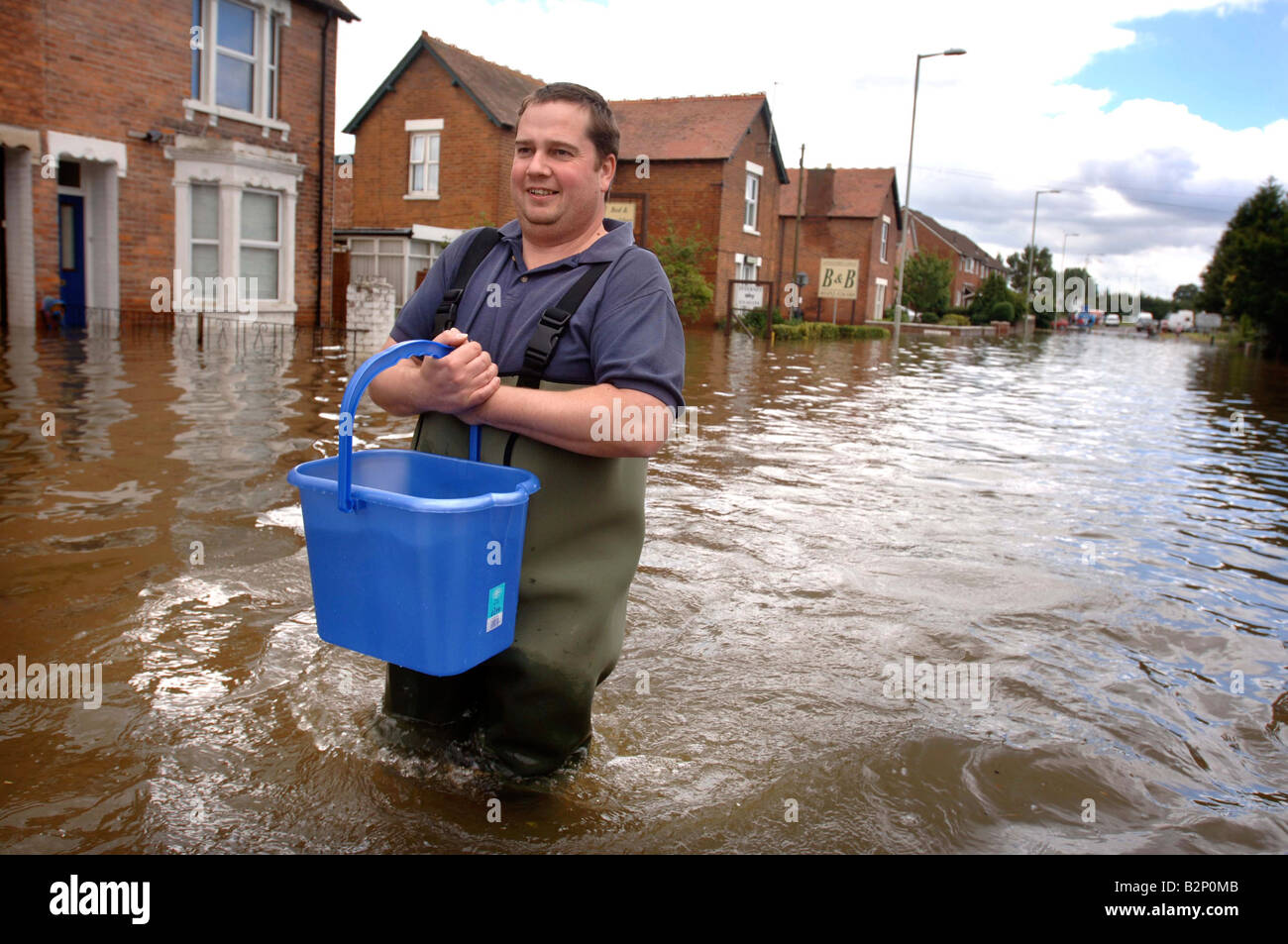 A MAN WEARING WADERS COLLECTS A BUCKET OF FRESH WATER DUE TO ...