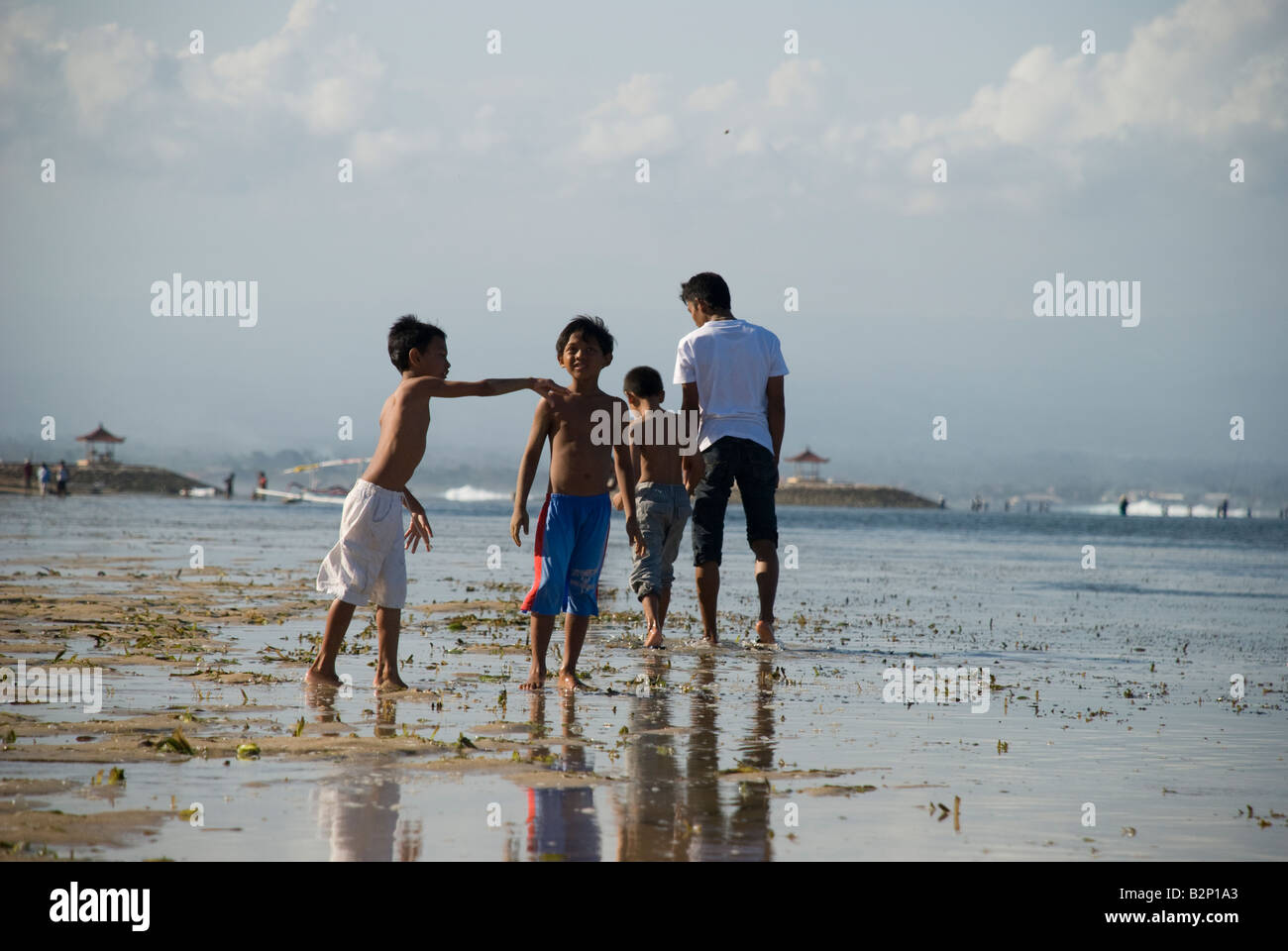 bali indonesia boys brothers friends playing beach throw sand water sea ...