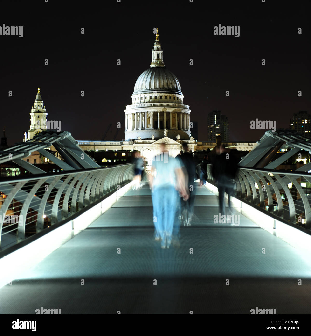 people walking over the Millennium Bridge at night in London with st ...