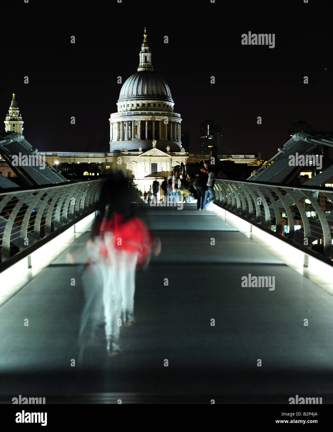 people walking over the Millennium Bridge at night in London with st ...