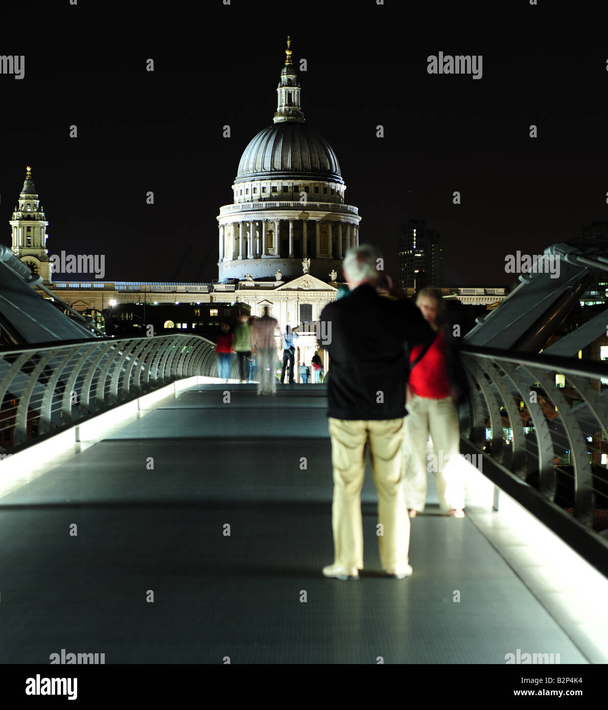people walking over the Millennium Bridge at night in London with st ...