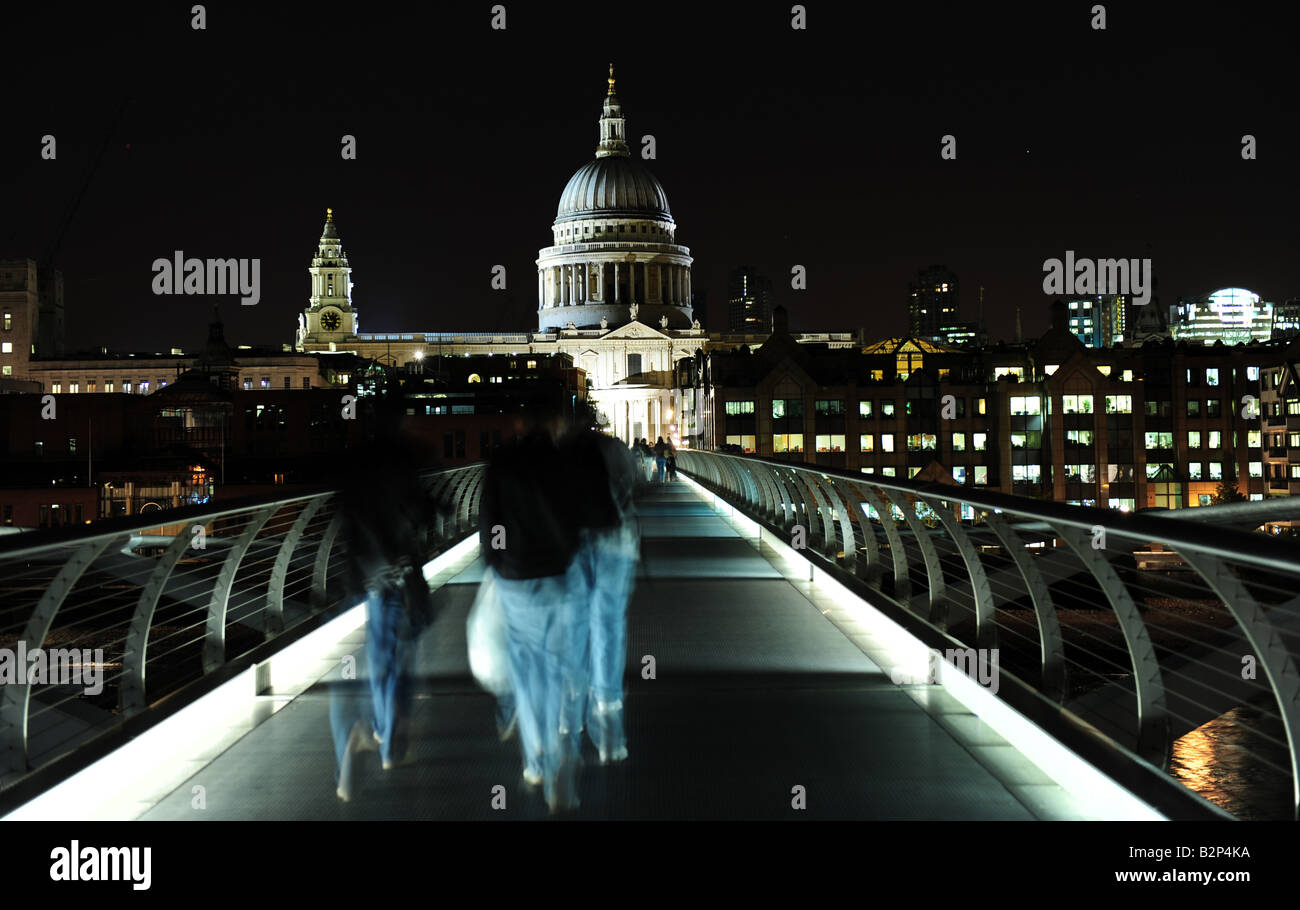 people walking over the Millennium Bridge at night in London with st ...