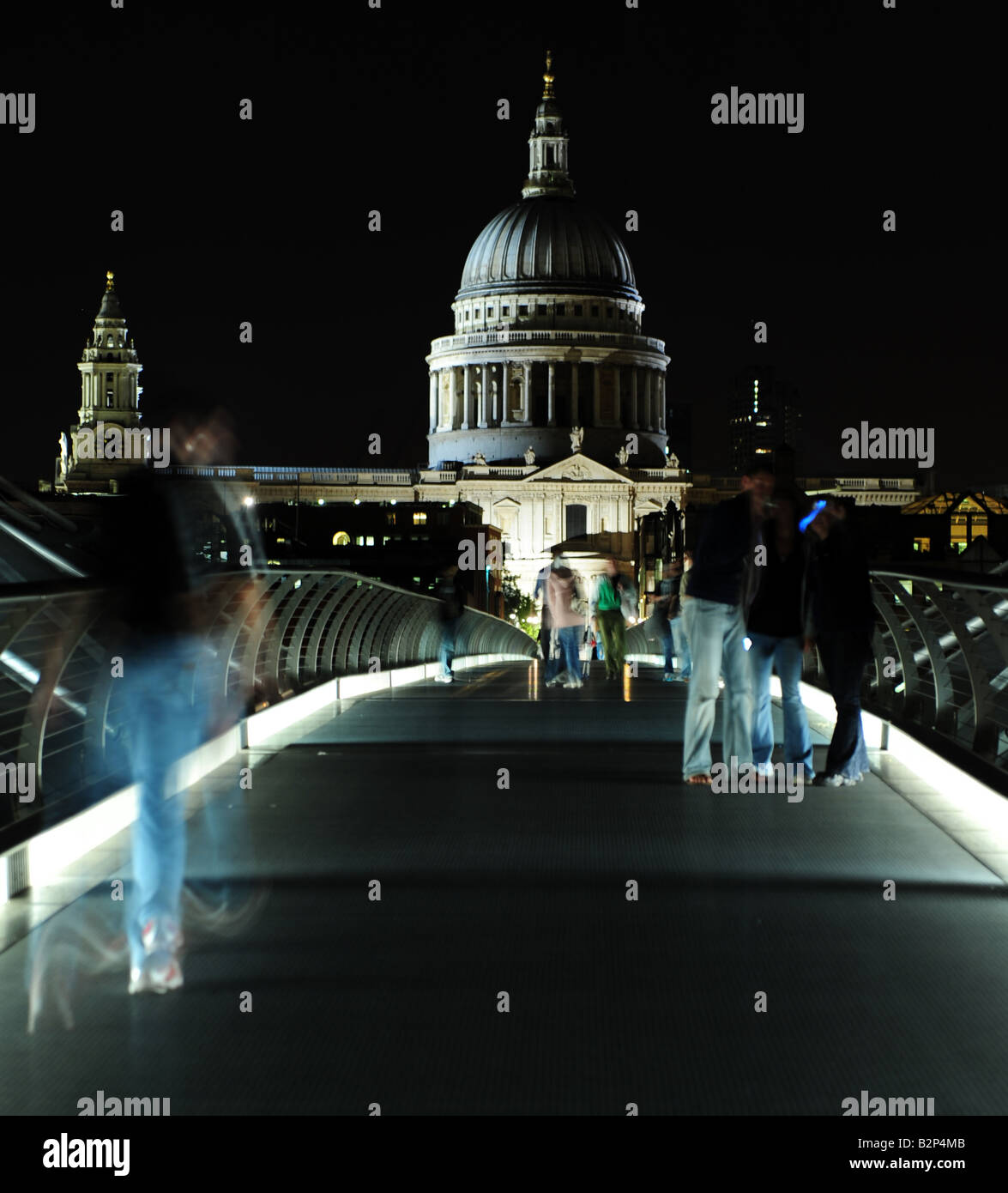 people walking over the Millennium Bridge at night in London with st ...