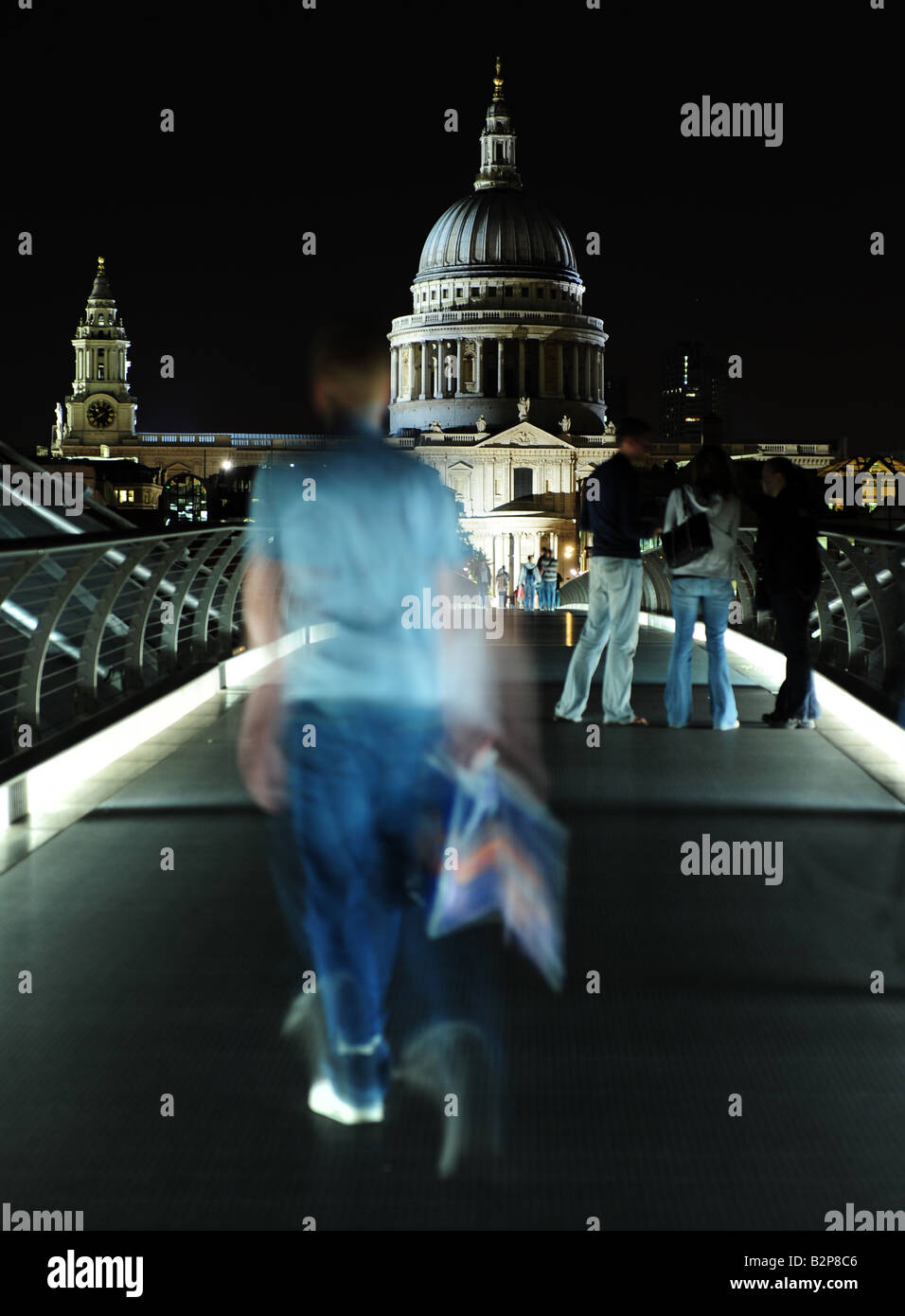people walking over the Millennium Bridge at night in London with st ...