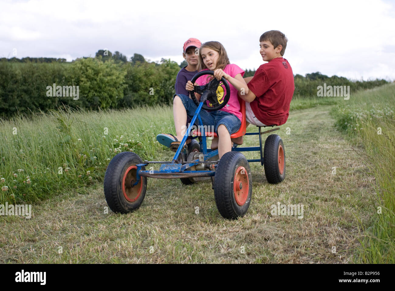 Children having fun on pedal go cart in farm field Cotswolds UK Stock ...