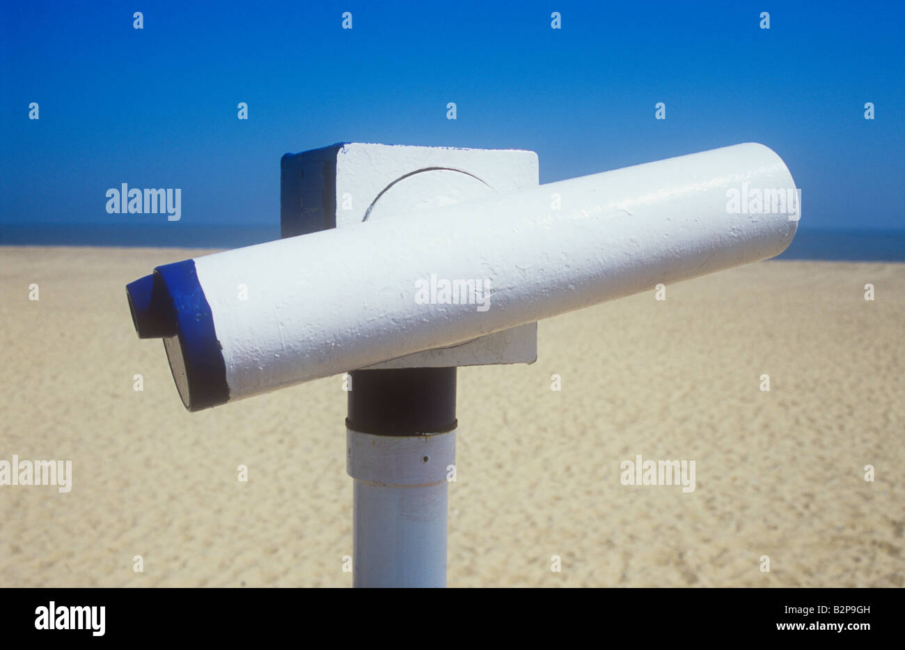 Close up of white and blue seaside telescope with soft pale sand and ...