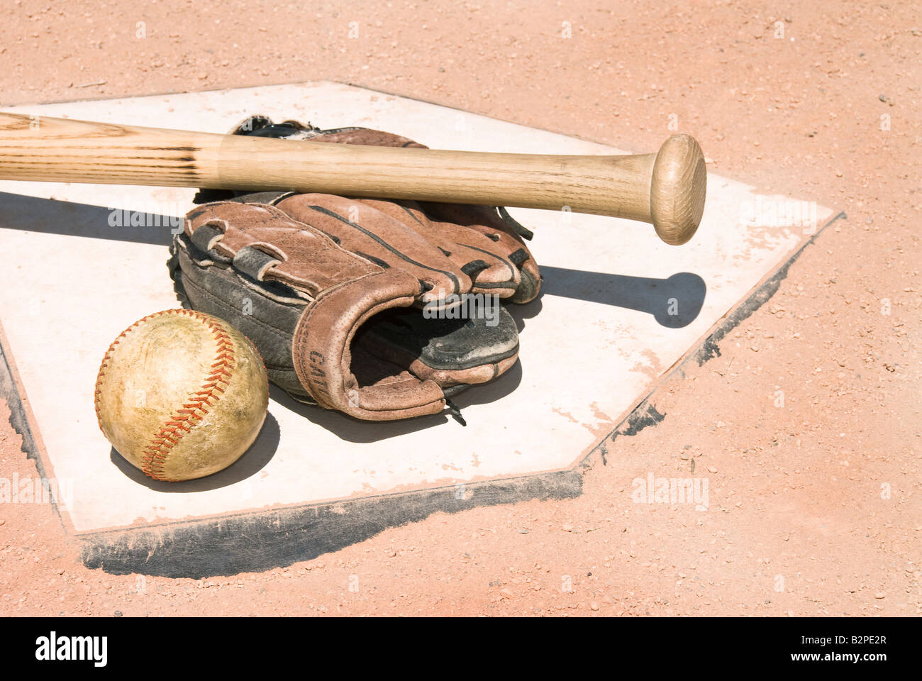A baseball bat glove and ball lie on top of home plate as a conceptual ...