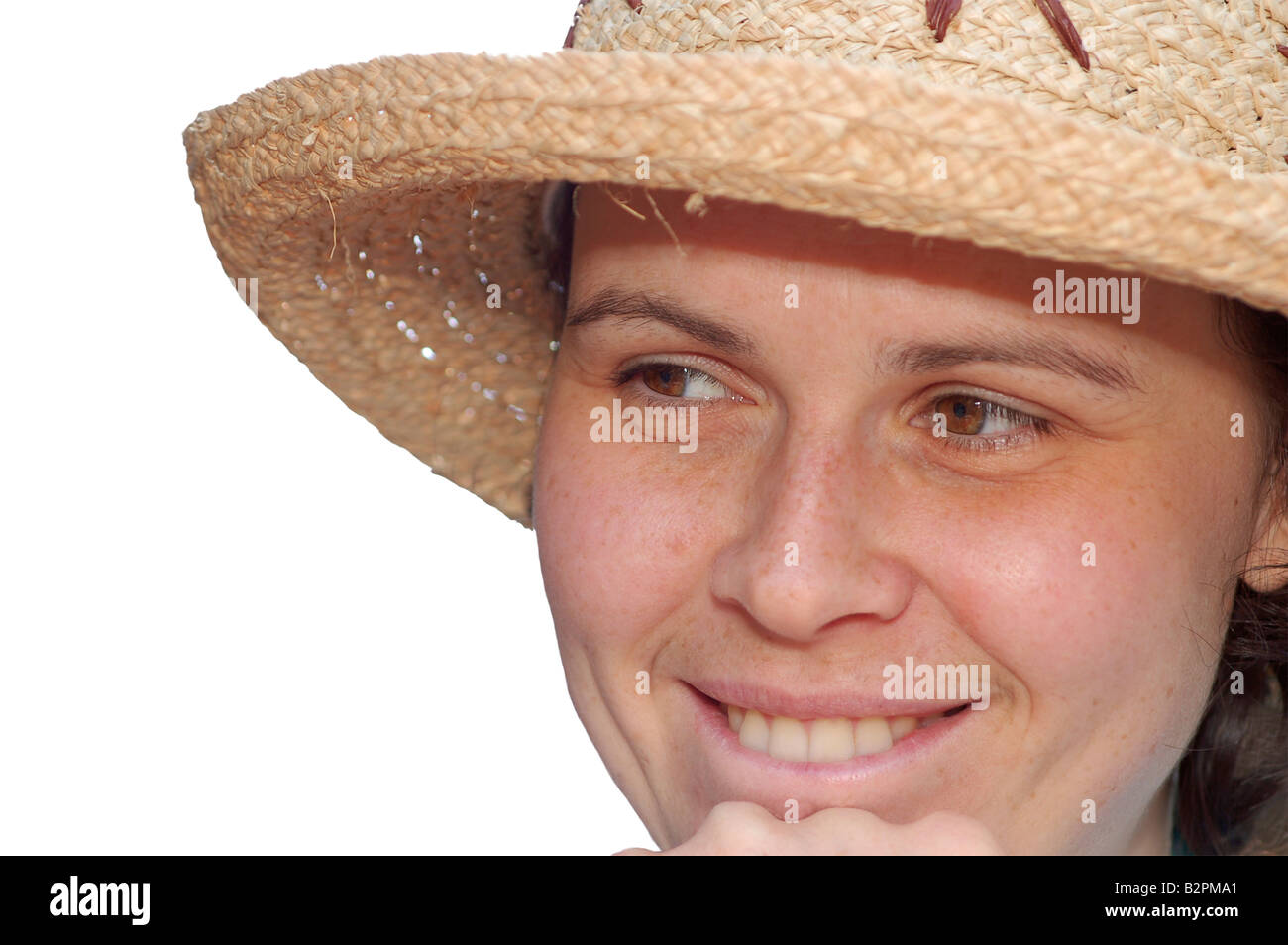 An attractive coquettish young girl in a straw hat smiles mischievously ...