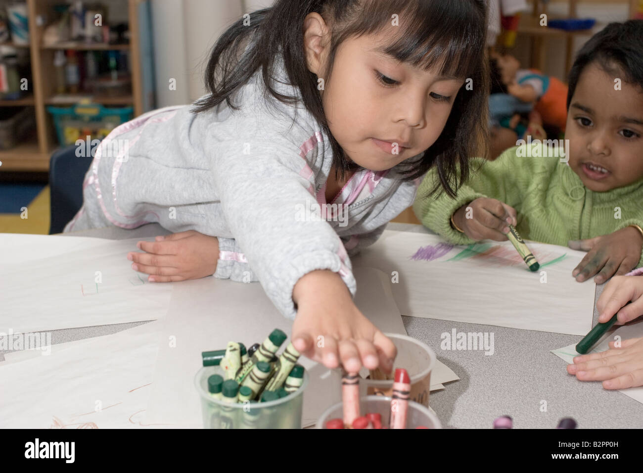 4 year old preschool girl reaching for a crayon to color with Stock ...
