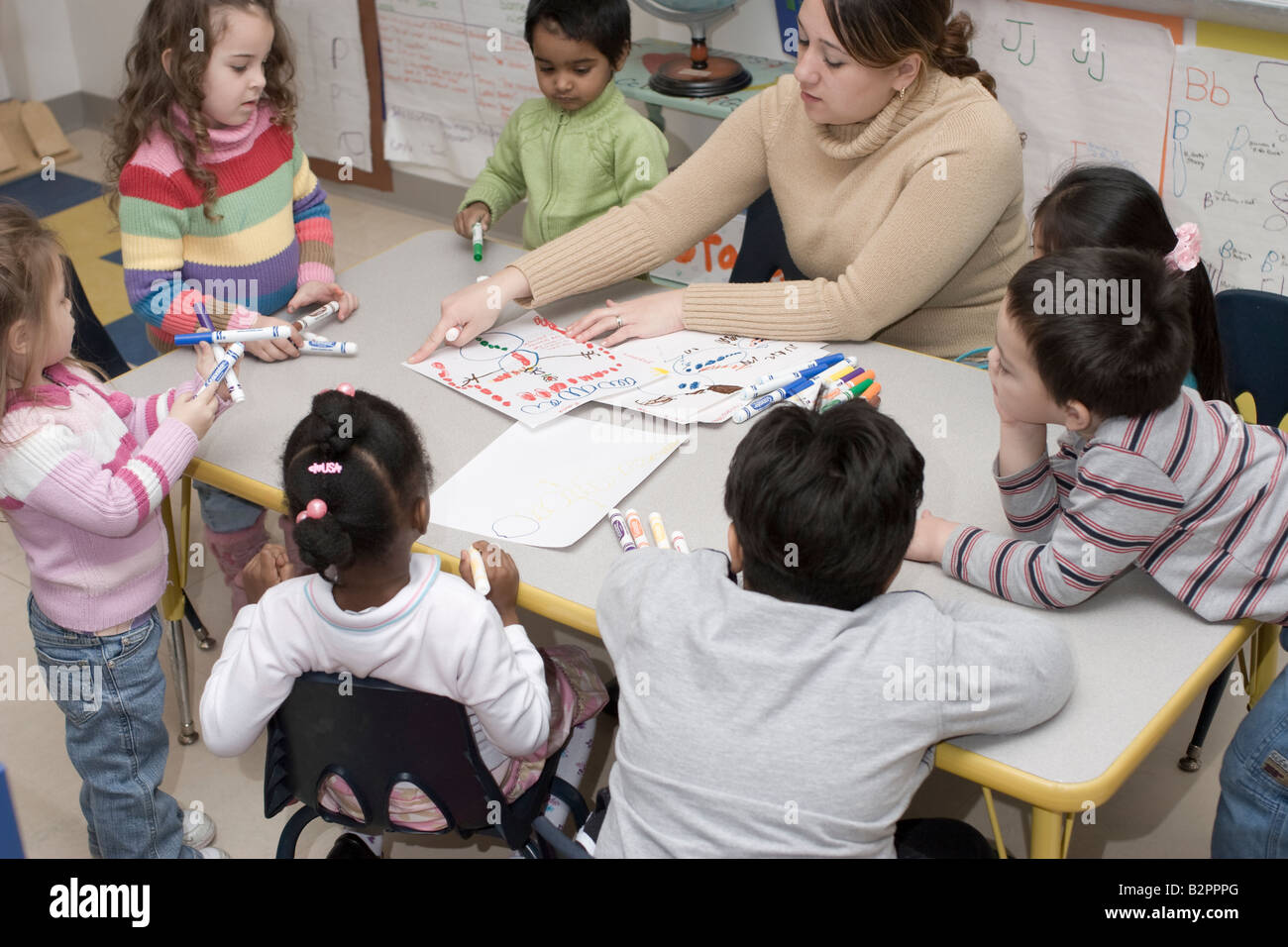 Preschool teacher helping her students learn to color Stock Photo - Alamy