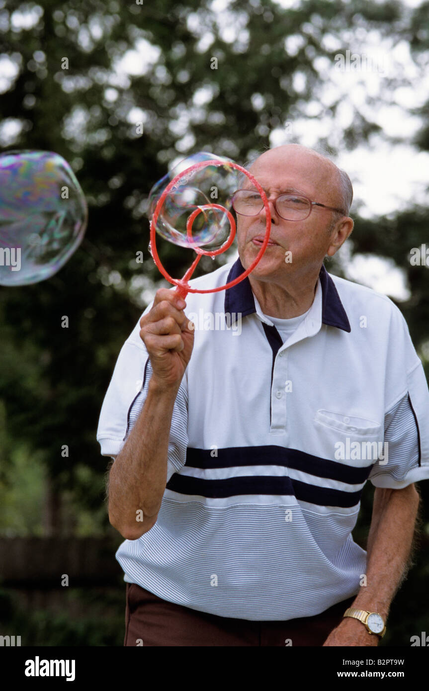Elderly man blowing bubbles in backyard Stock Photo - Alamy