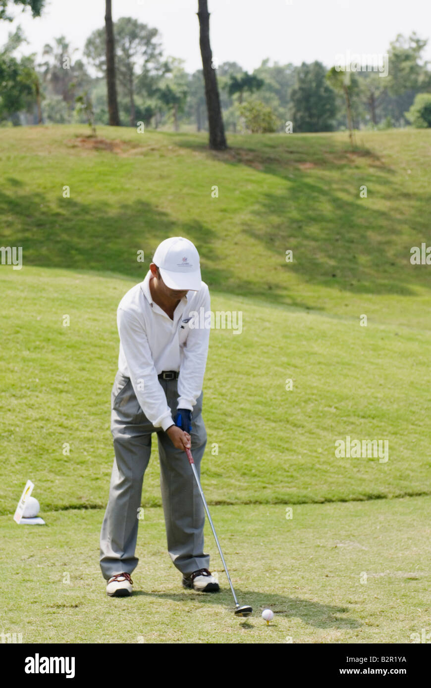 Man teeing off on golf course Stock Photo - Alamy