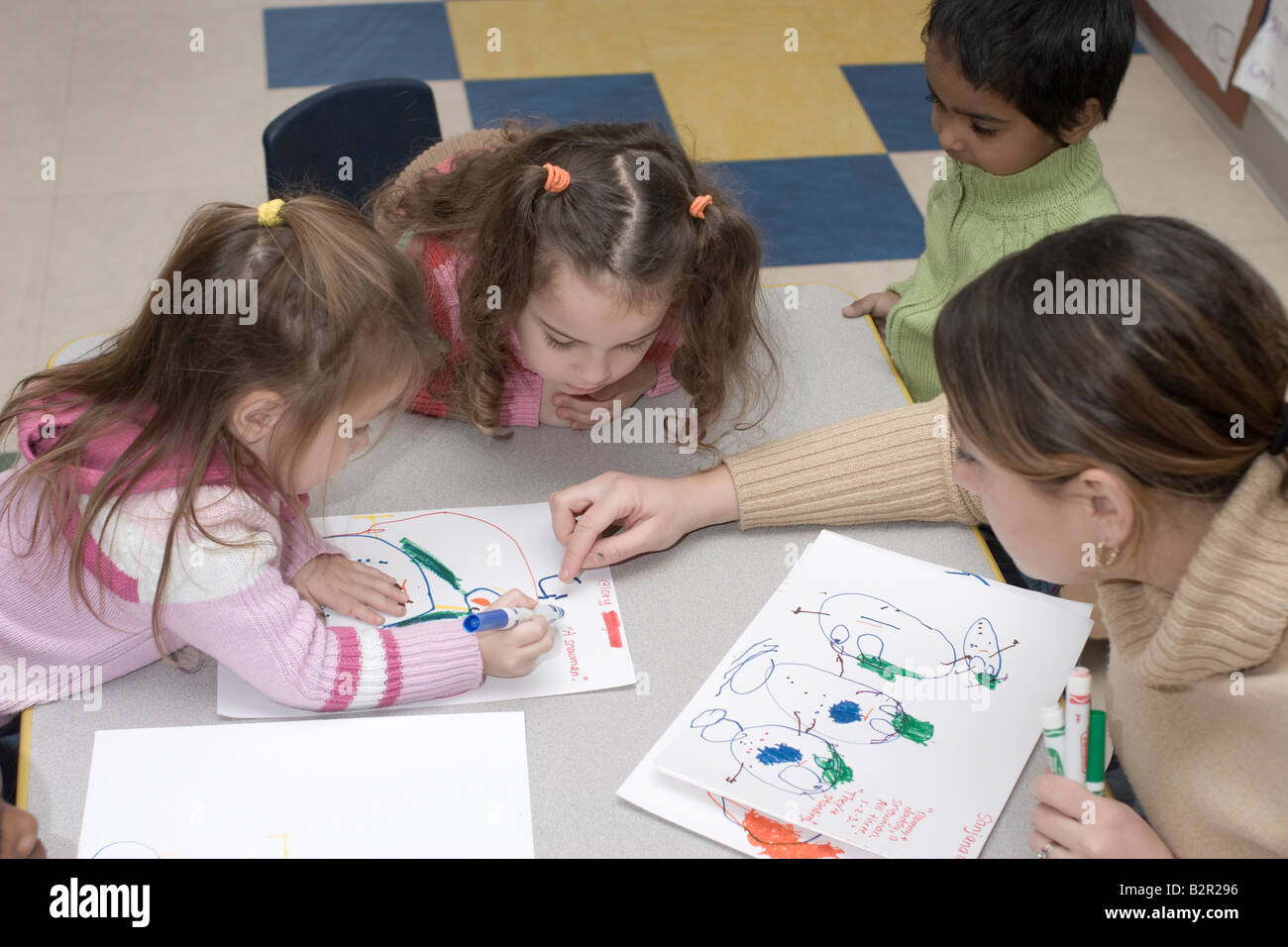 Preschool teacher helping her students learn to color Stock Photo - Alamy