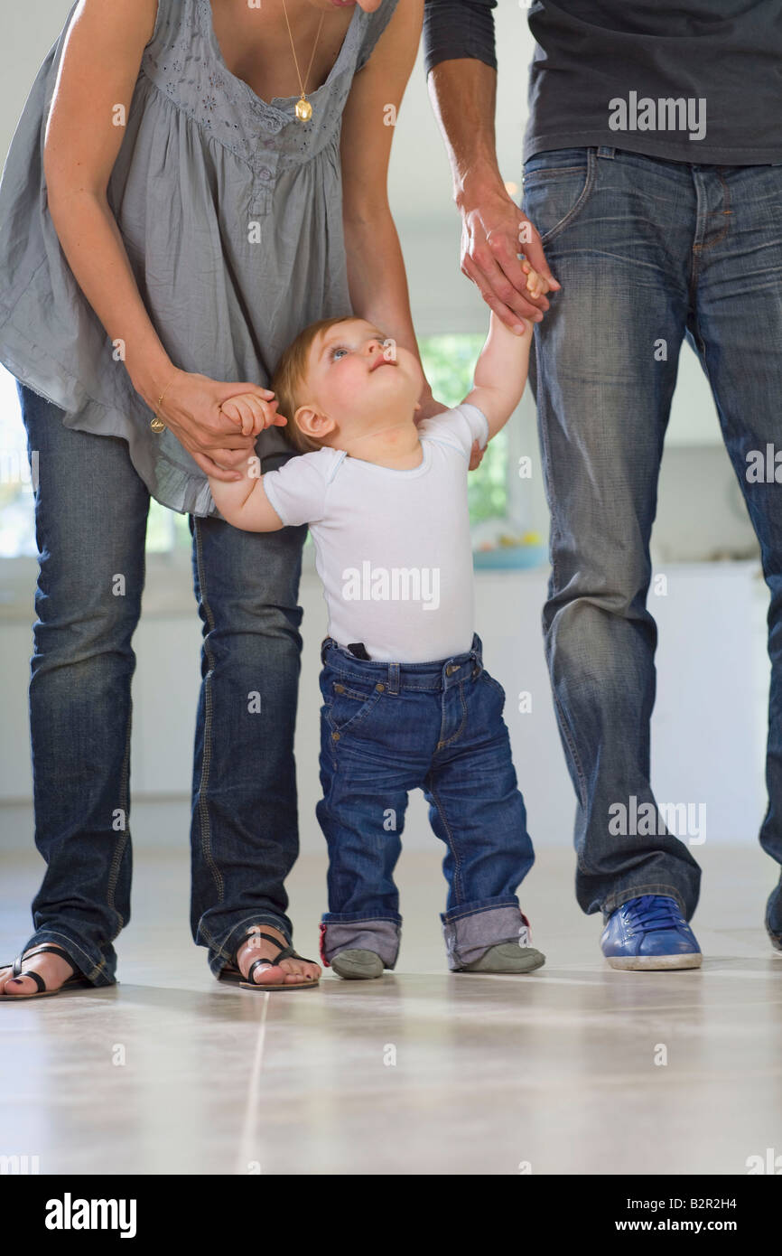 Baby walks looks to parents Stock Photo - Alamy