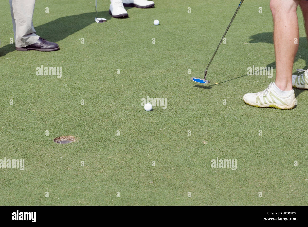 Close-up of golfer legs putting golf ball on green Stock Photo - Alamy