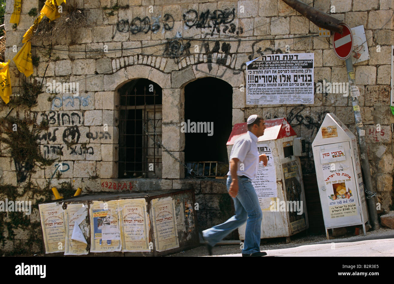 Man walking past graffiti and posters in Israel Stock Photo - Alamy