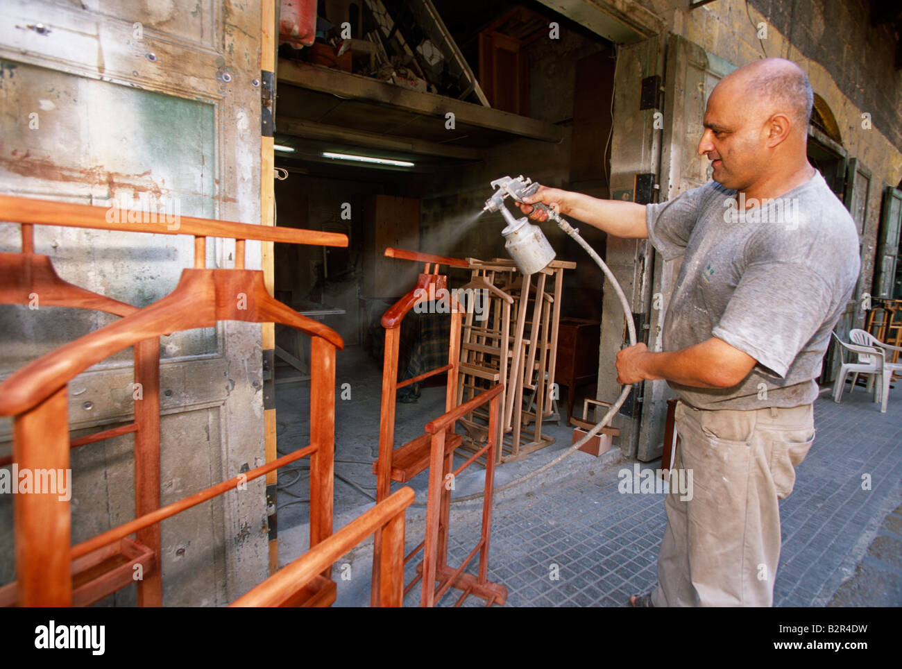 Worker spraying wooden valet stand outside workshop, Beirut, Lebanon ...