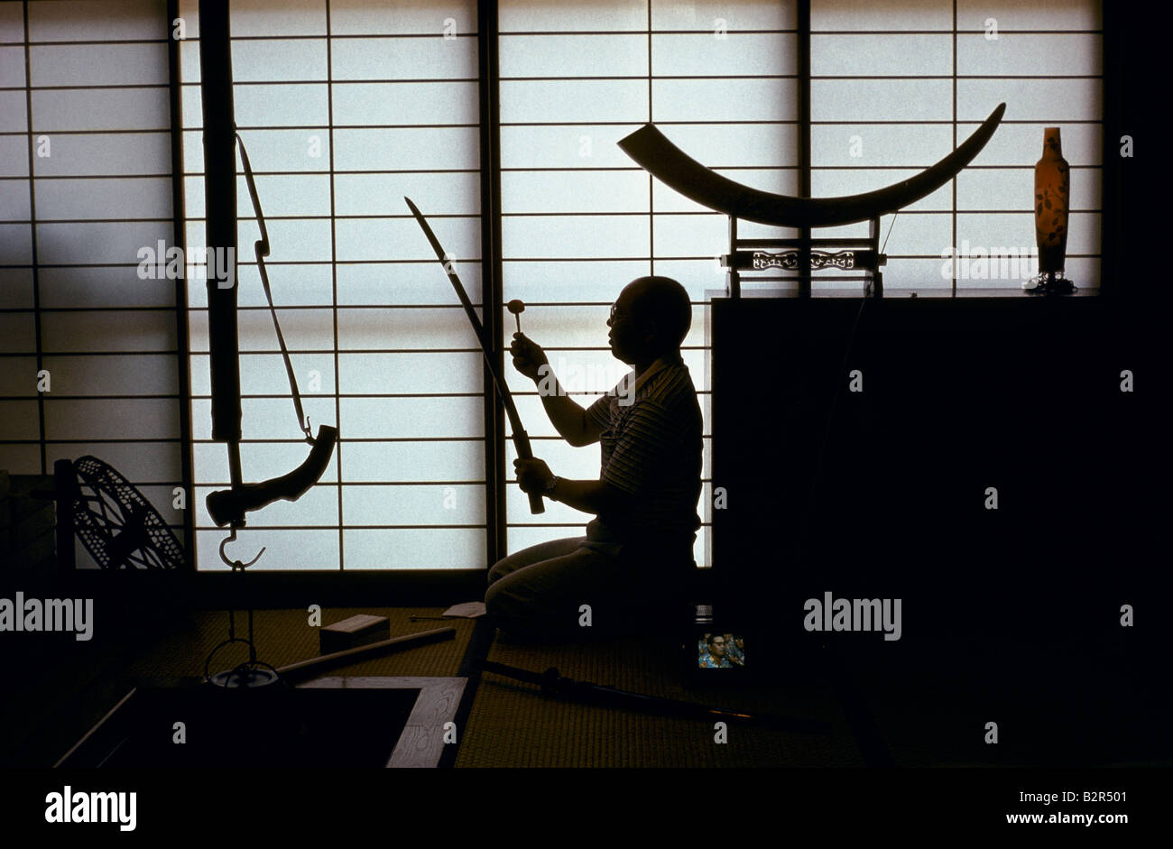 a man cleaning his antique ceremonial samurai sword in his japanese ...