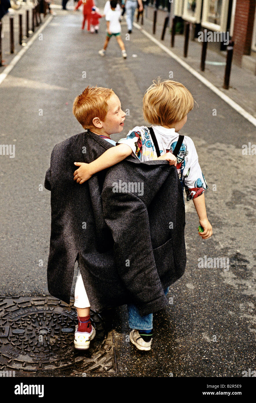 two children share an adult-sized jacket in a hug Stock Photo - Alamy