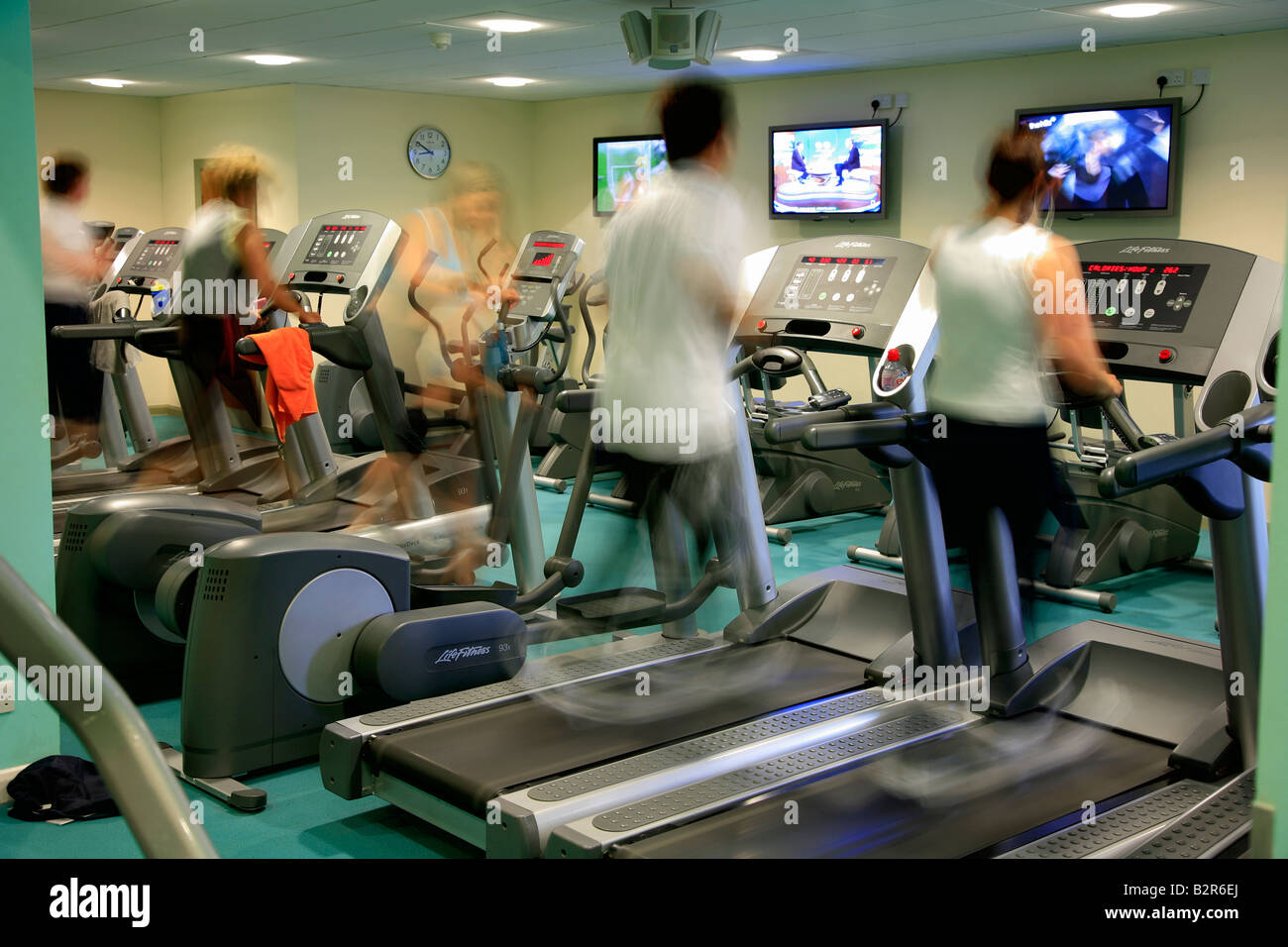People at the gym on running machines blurred for speed power effects ...