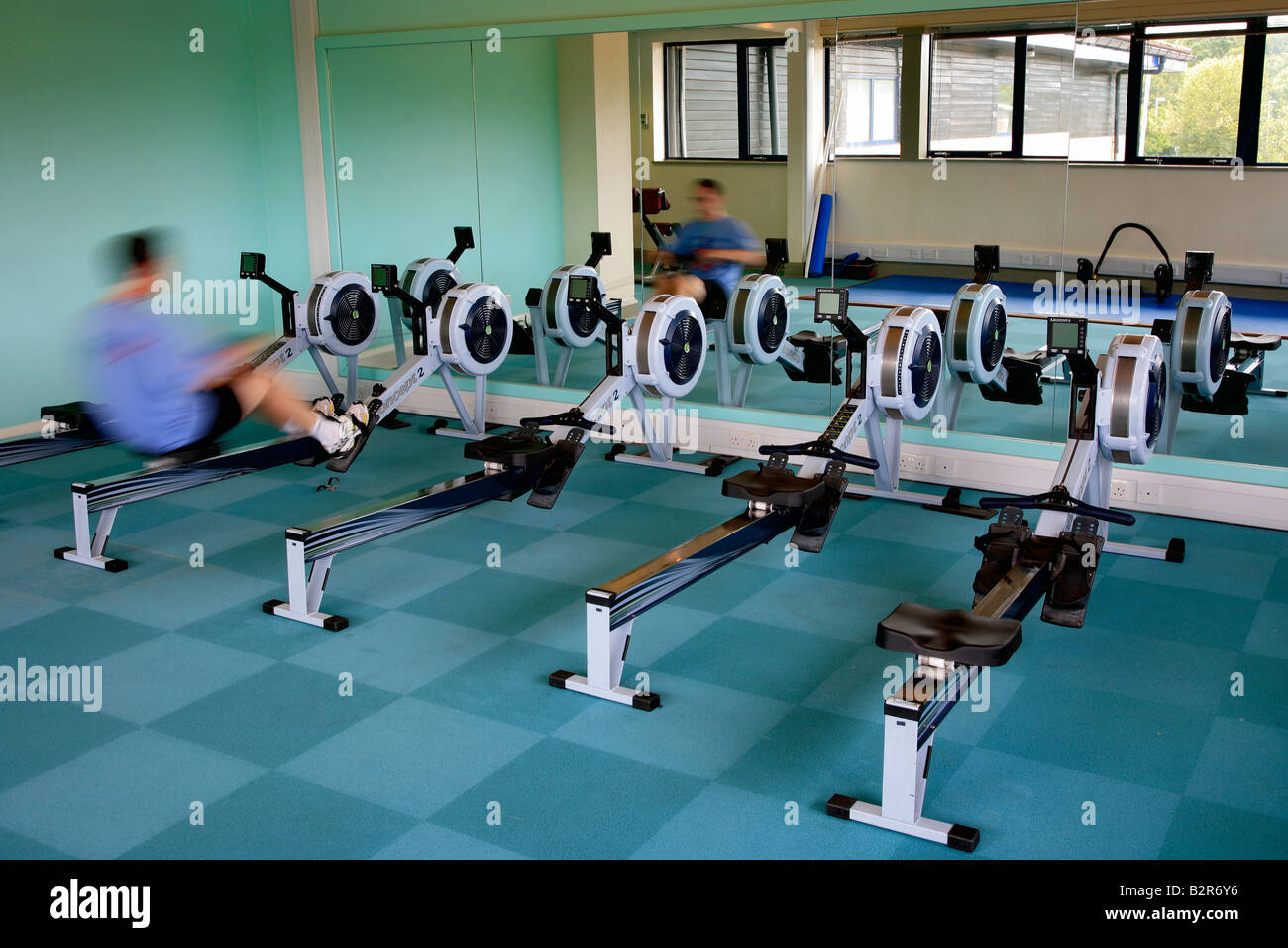 People at the gym on rowing machines, blurred for speed and power ...