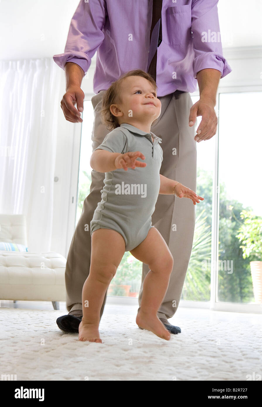 Father watching baby walking Stock Photo - Alamy