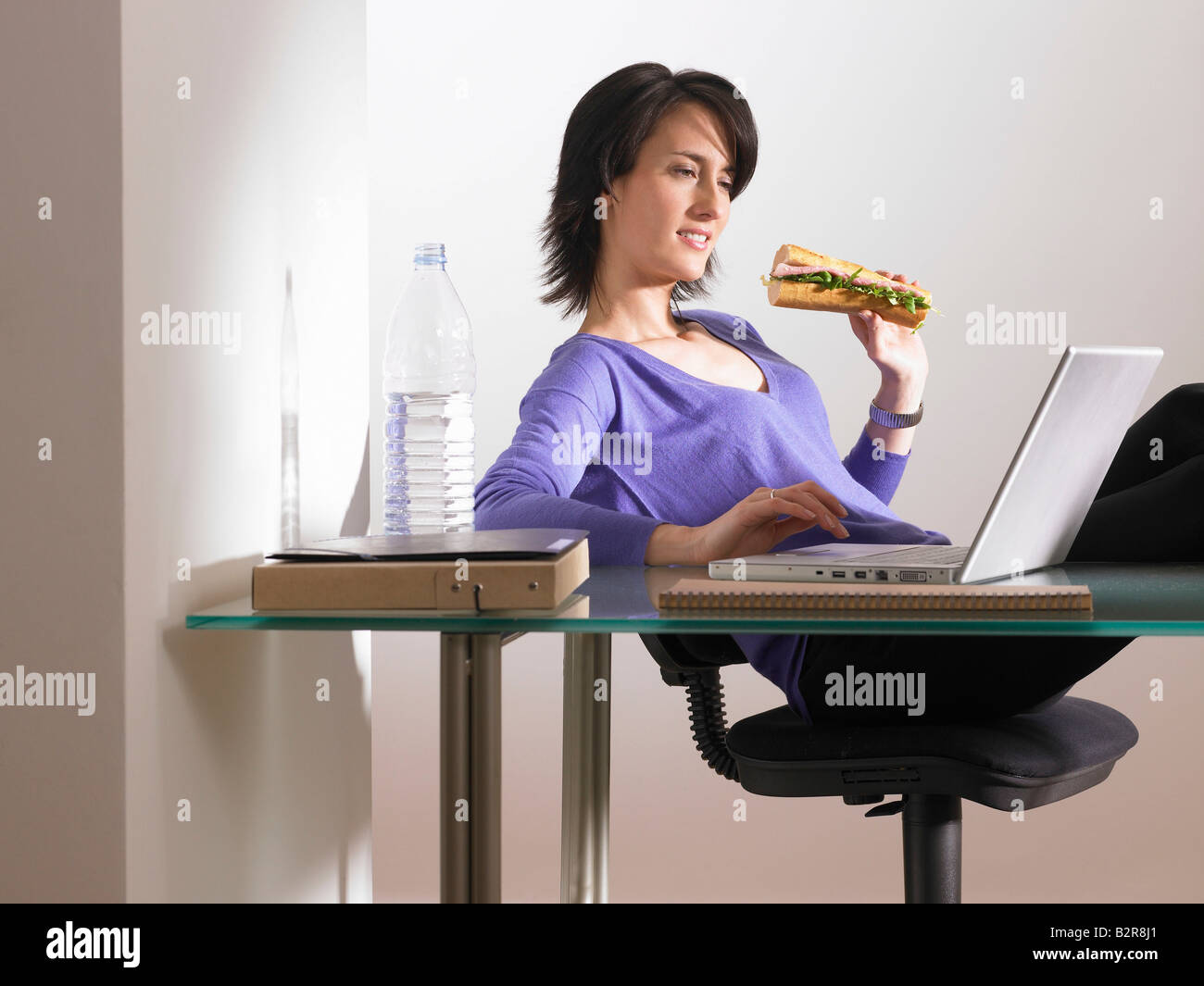 Woman at her desk, eating Stock Photo - Alamy