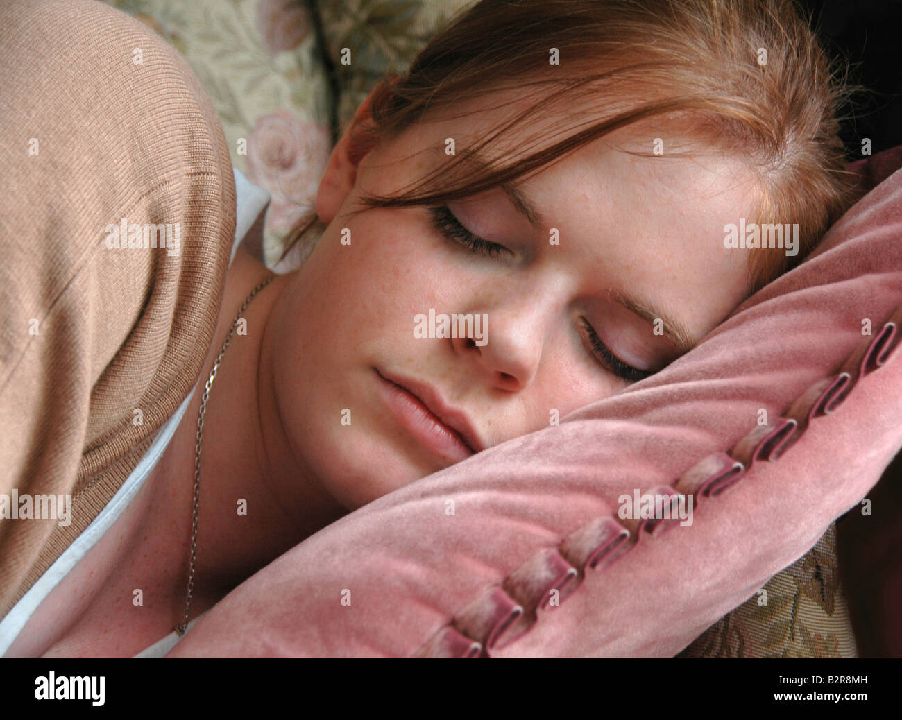 A teenage girl takes a nap ,resting her head on a settee cushion Stock ...