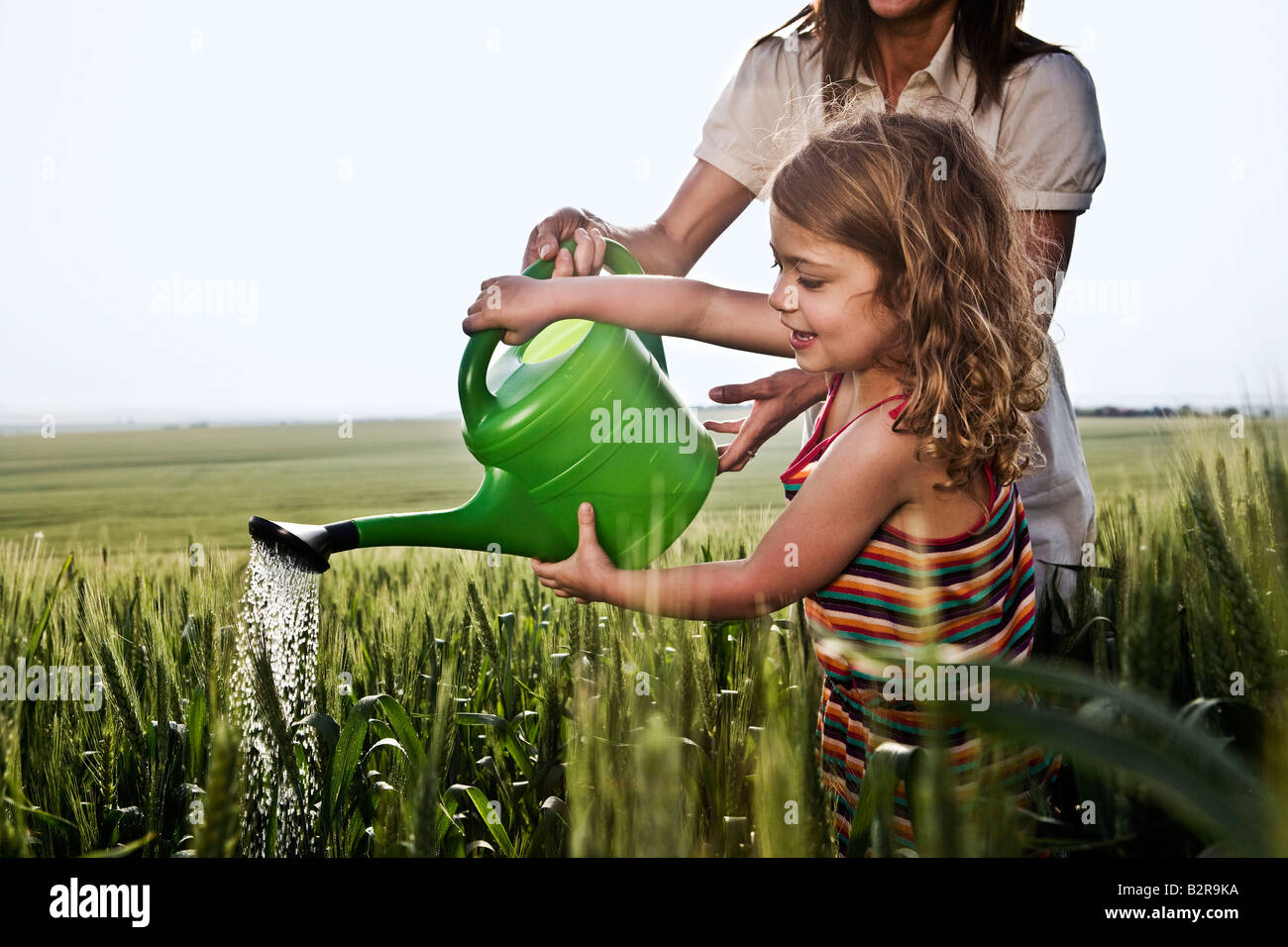 Woman and child with watering can Stock Photo - Alamy
