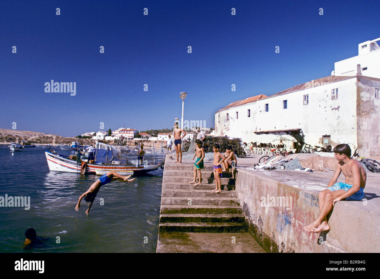 child doing acrobatic diving in ferragudos harbour while some of his ...