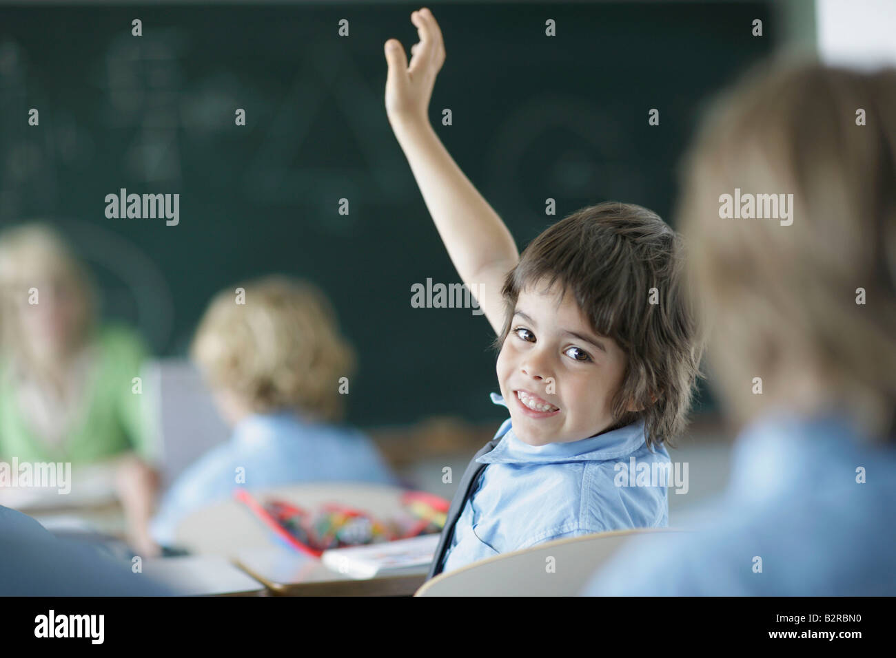 School boy raising hand in class Stock Photo - Alamy