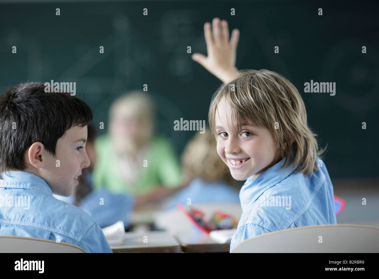 School boy raising hand in class Stock Photo - Alamy